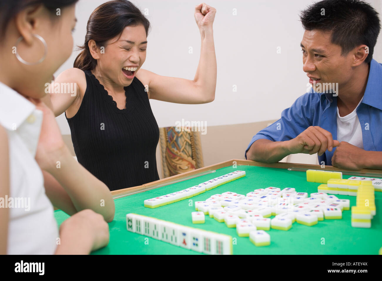 Young woman cheering while playing mahjong Stock Photo - Alamy