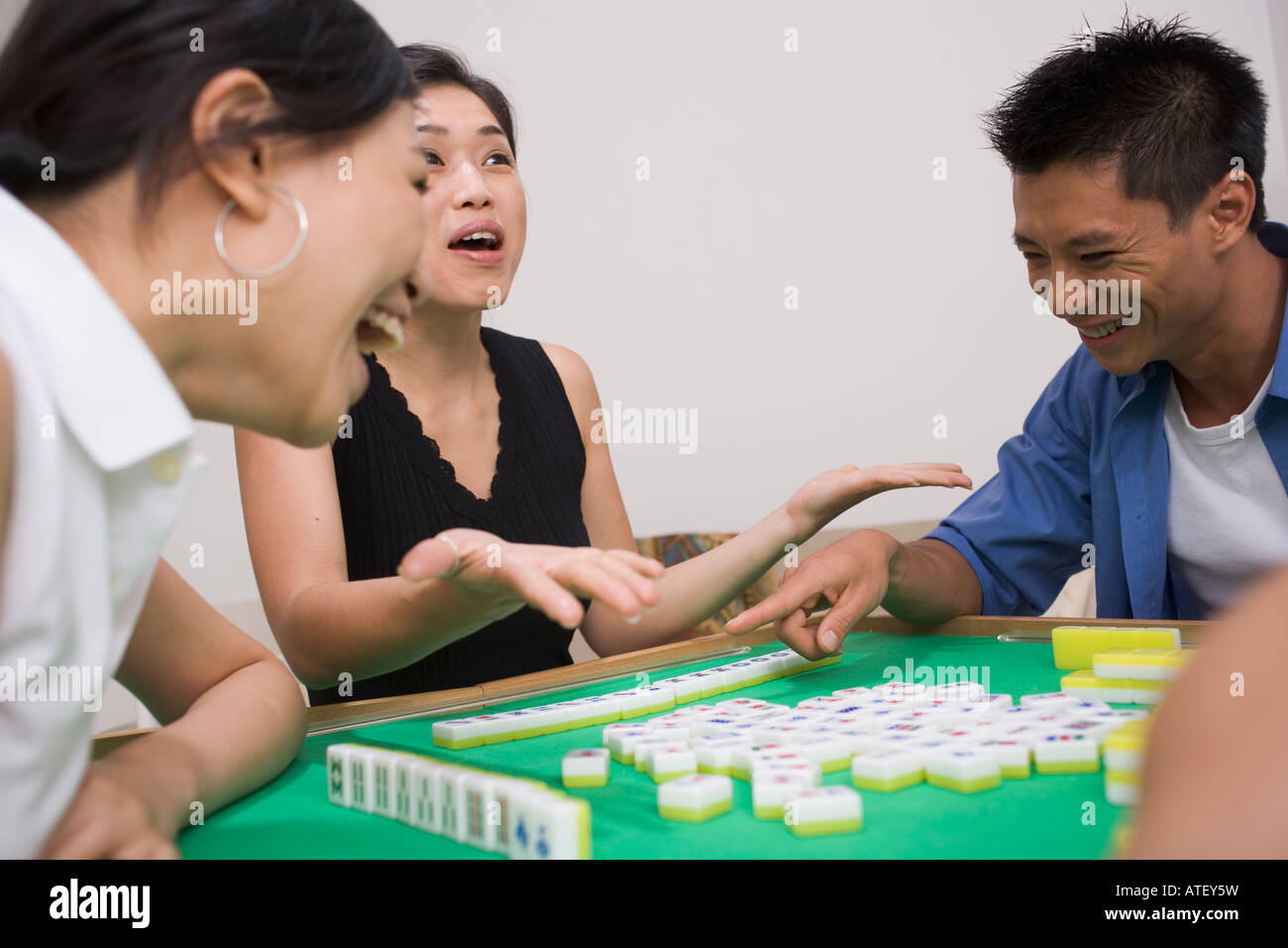 Two young women and a young man playing mahjong Stock Photo - Alamy