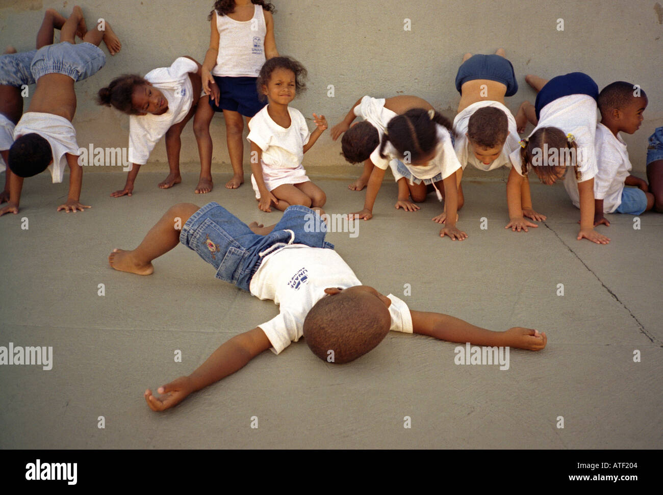 Portrait group school boy girl outdoor play learn capoeira lie floor ...