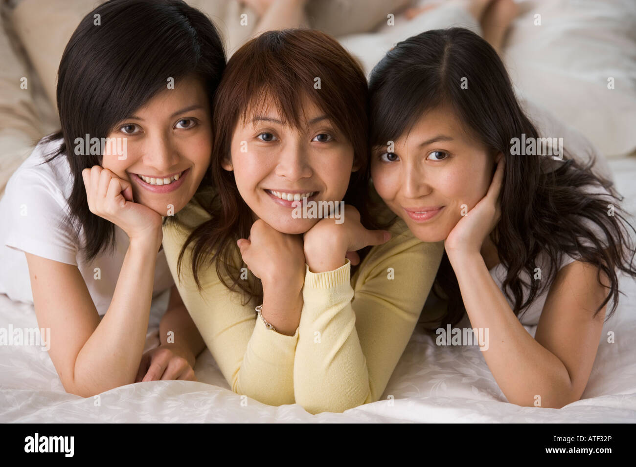 Portrait of three sisters lying on the bed Stock Photo - Alamy