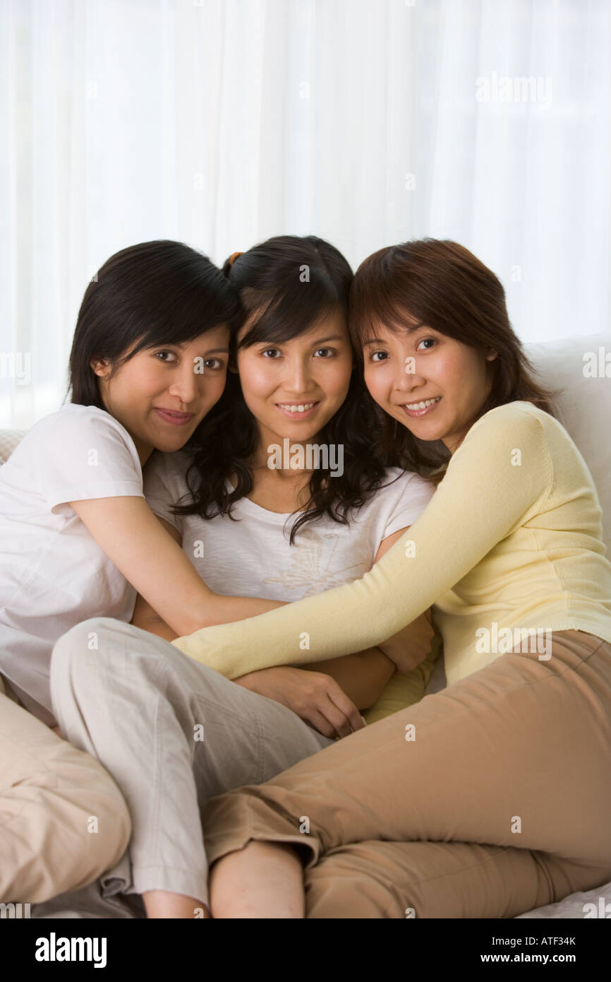 Portrait of two young women hugging their sister on the bed Stock Photo ...