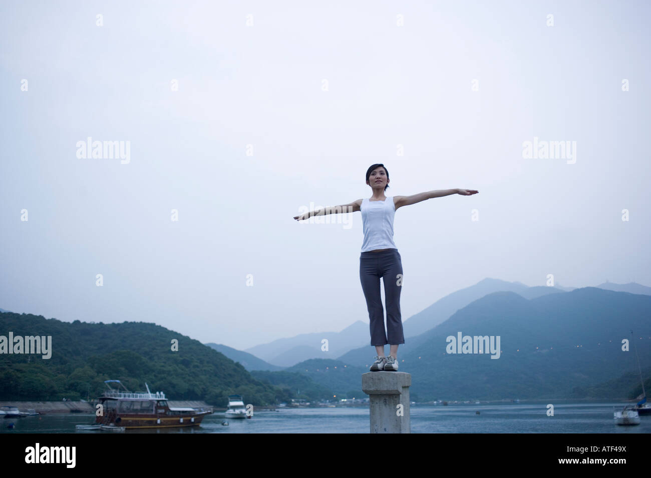 Portrait of a young woman balancing on a cement block Stock Photo - Alamy