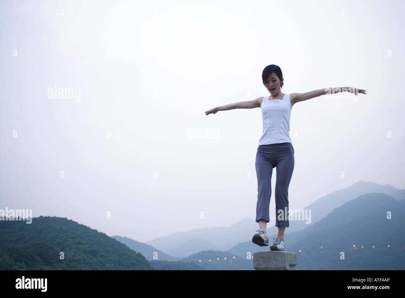Portrait of a young woman balancing on a cement block Stock Photo - Alamy