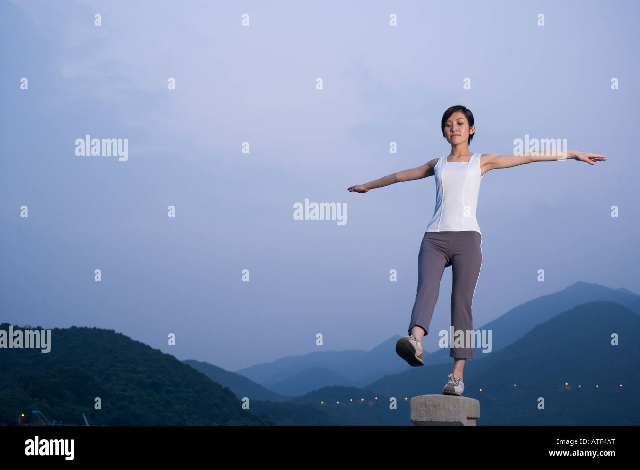 Portrait of a young woman balancing on a cement block Stock Photo - Alamy