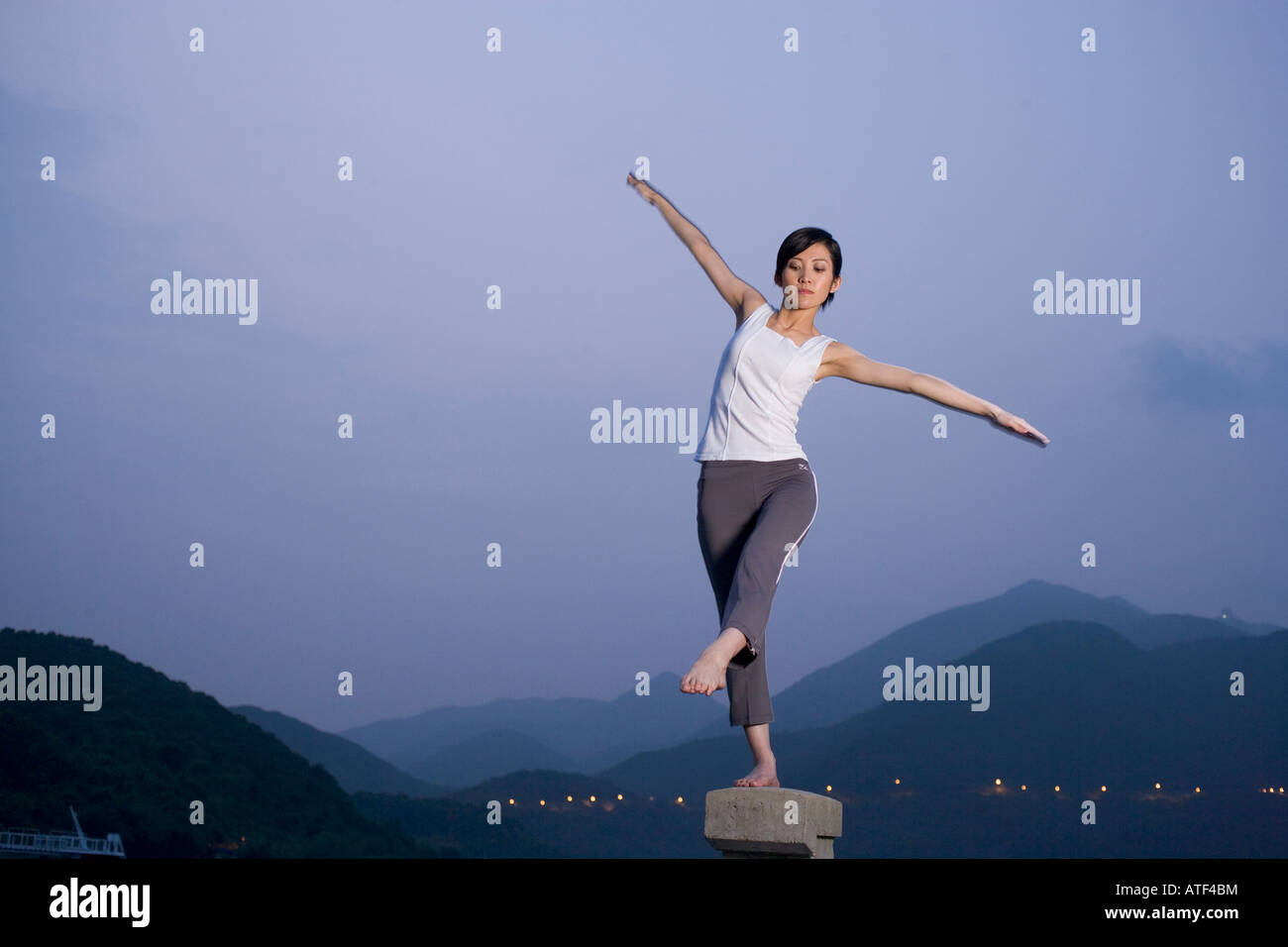 Portrait of a young woman balancing on a cement block Stock Photo - Alamy