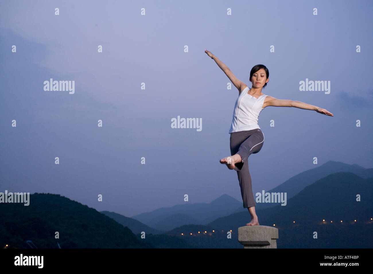 Portrait of a young woman balancing on a cement block Stock Photo - Alamy