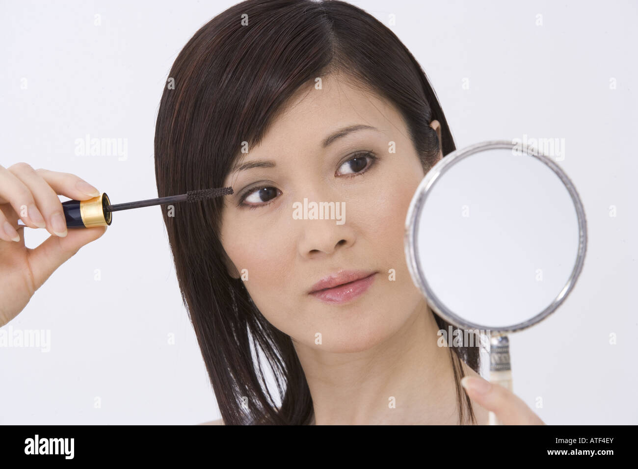 Portrait of a mid adult woman putting on eye liner Stock Photo - Alamy