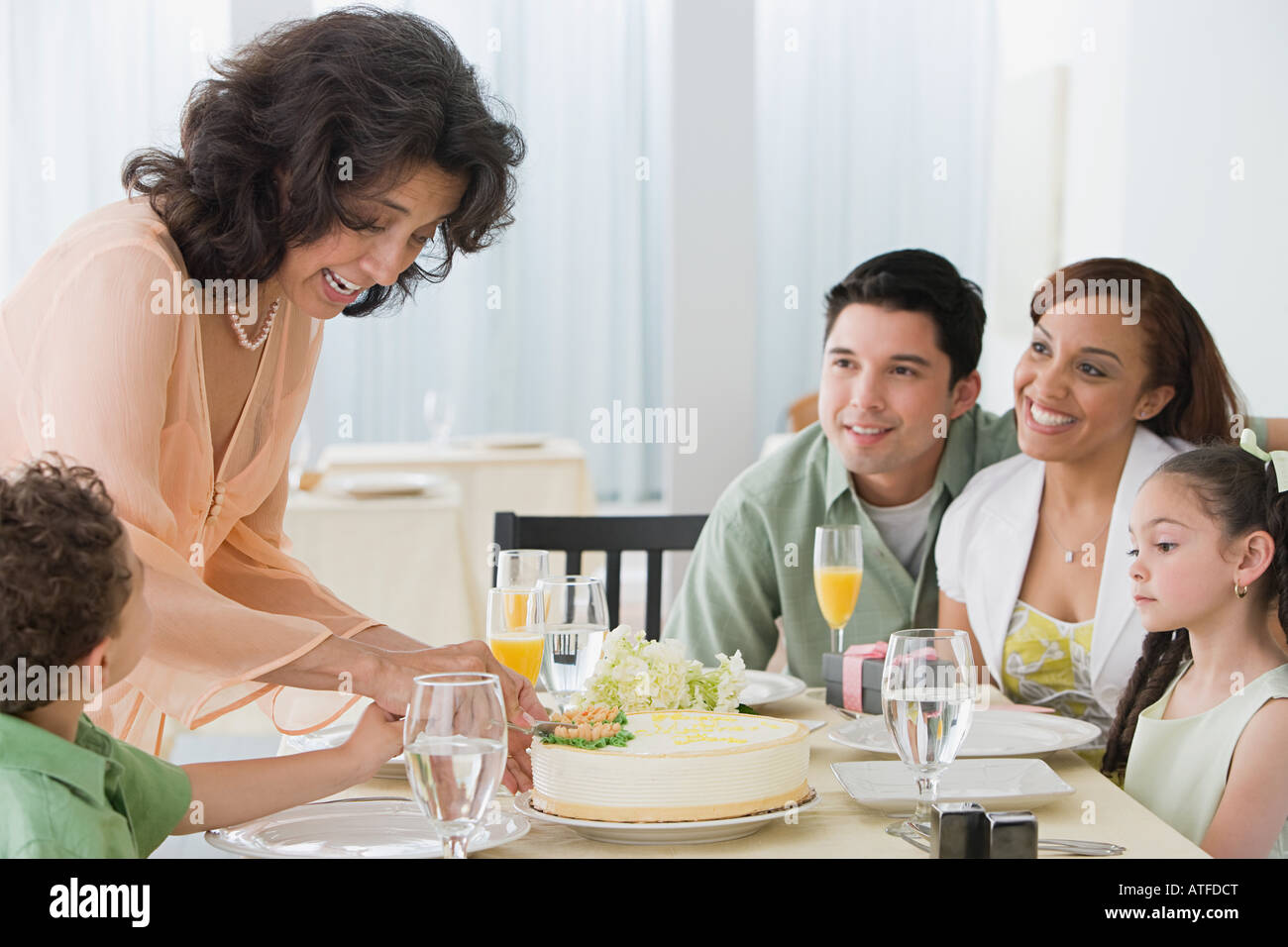 Woman cutting cake with family Stock Photo - Alamy