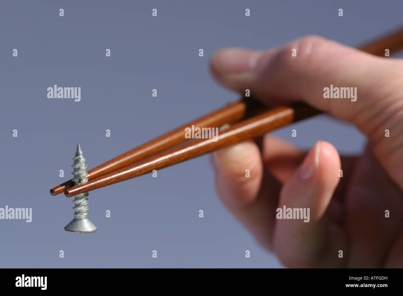 Hand holding chop sticks picking up screw Stock Photo - Alamy