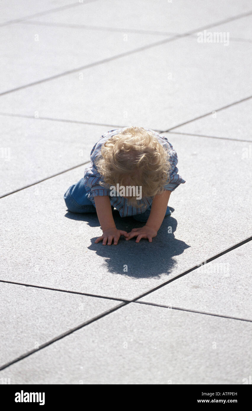 Kid kneeling on the ground Stock Photo - Alamy