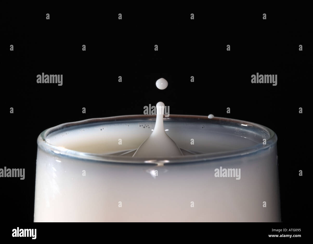 Milk drop splashing into full glass Stock Photo - Alamy