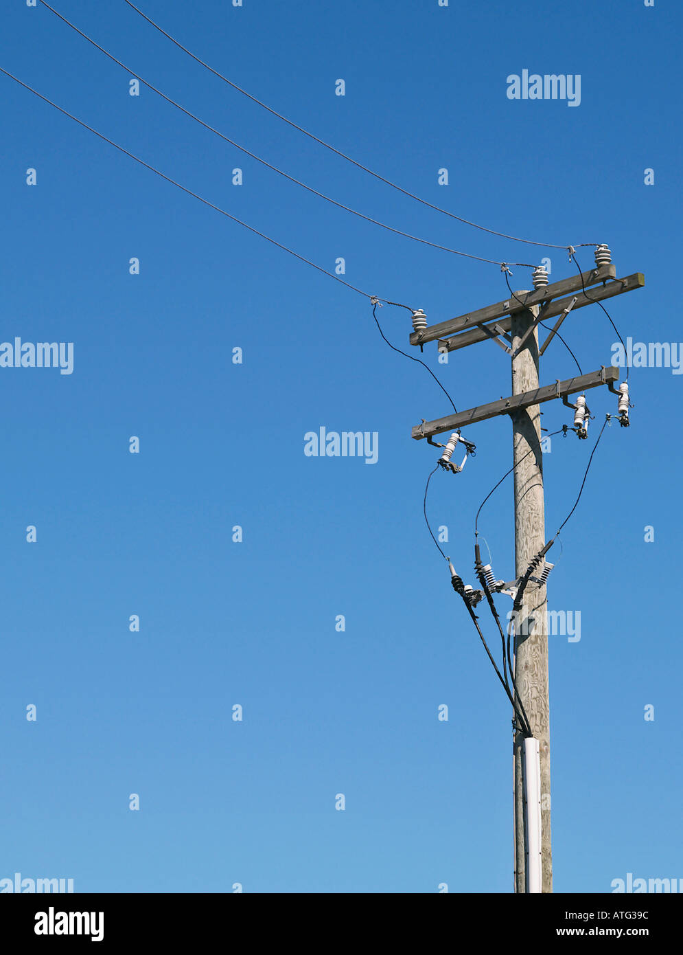 Power lines link to pole against blue sky Stock Photo - Alamy