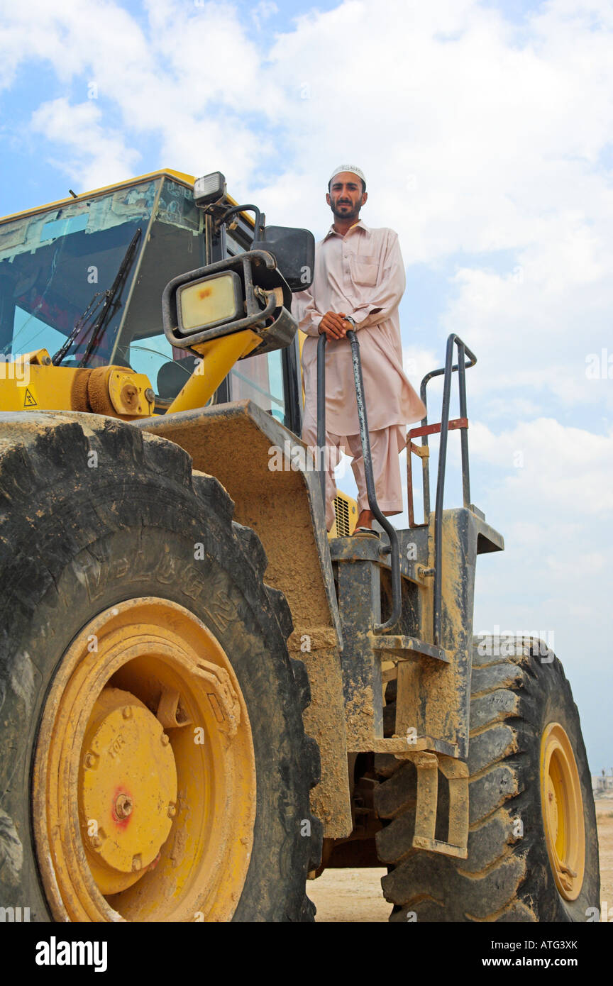 Workman standing on heavy earth moving machinery in new highway ...