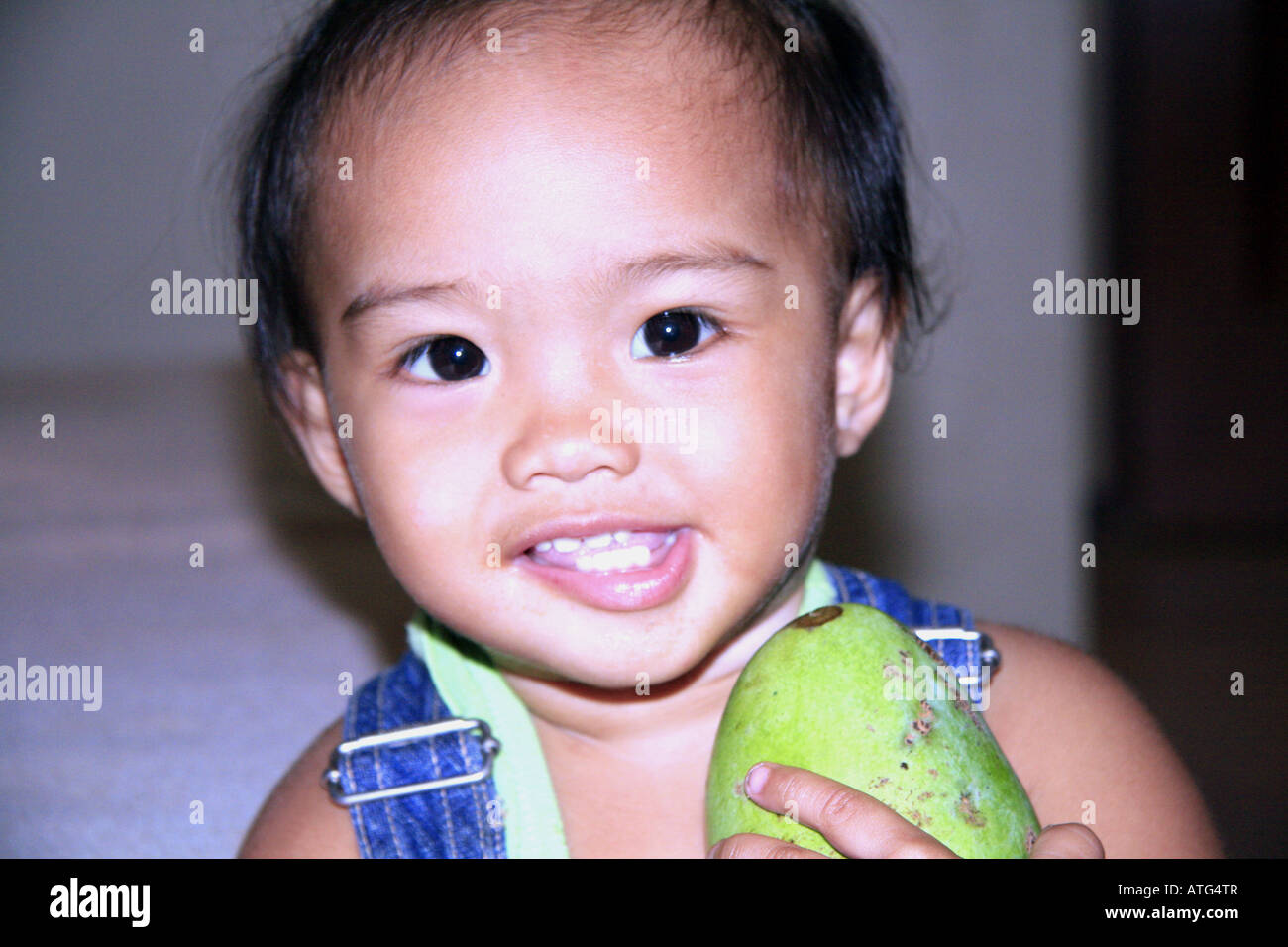 Little girl Rhys holding a green Mango with a pretty smile taken in ...