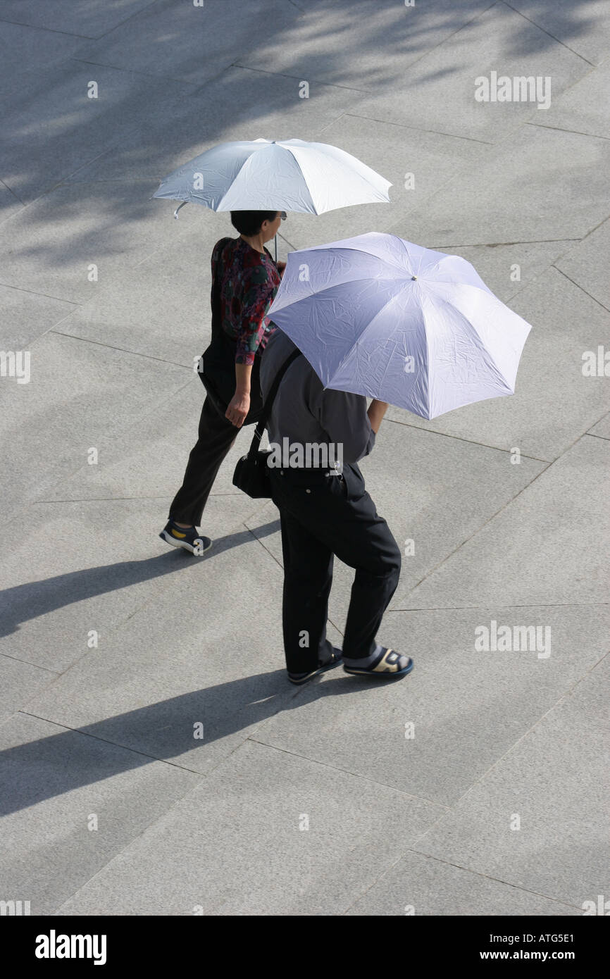 Couple use umbrellas to protect themselves from the sun Singapore Stock ...