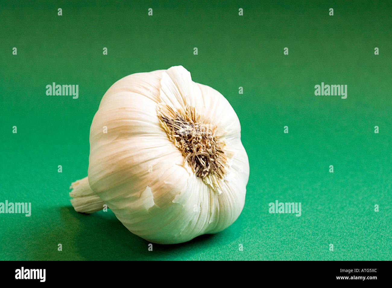 One clove of garlic on a green background Stock Photo - Alamy