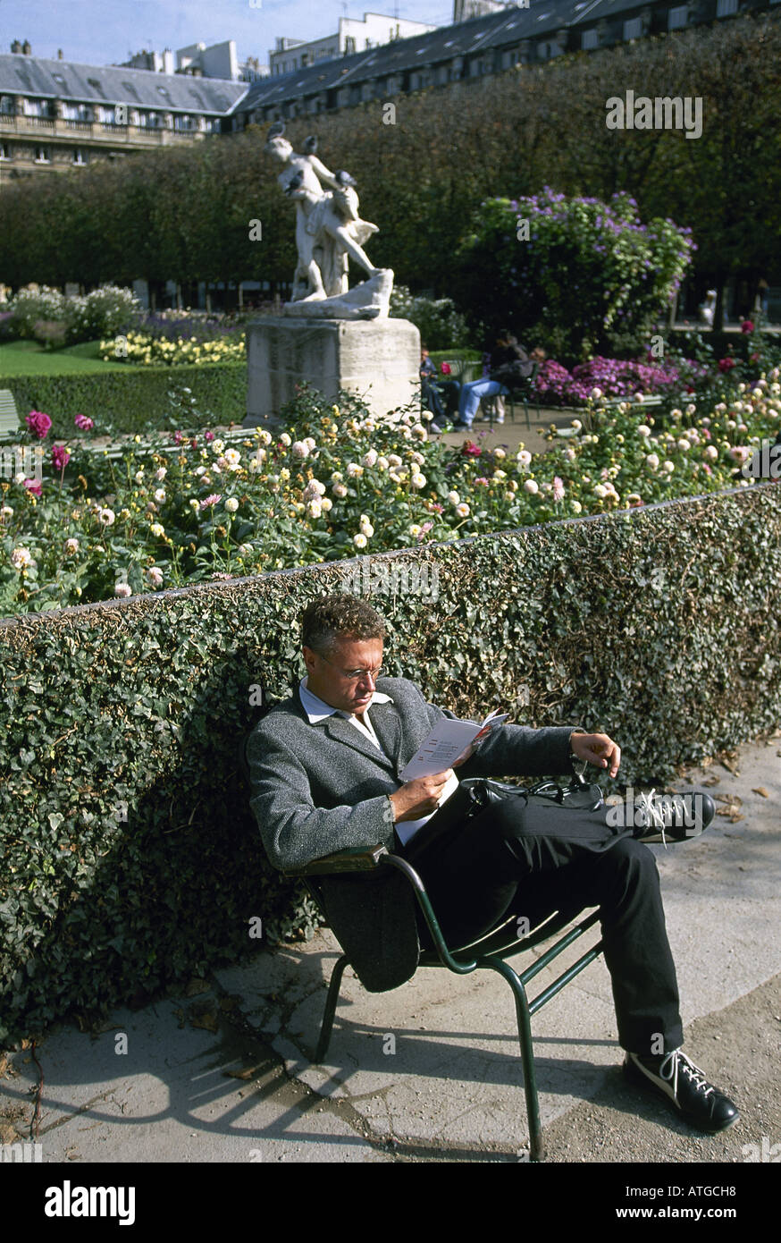 A man sat on a bench reading at the Palais Royal Paris Stock Photo - Alamy