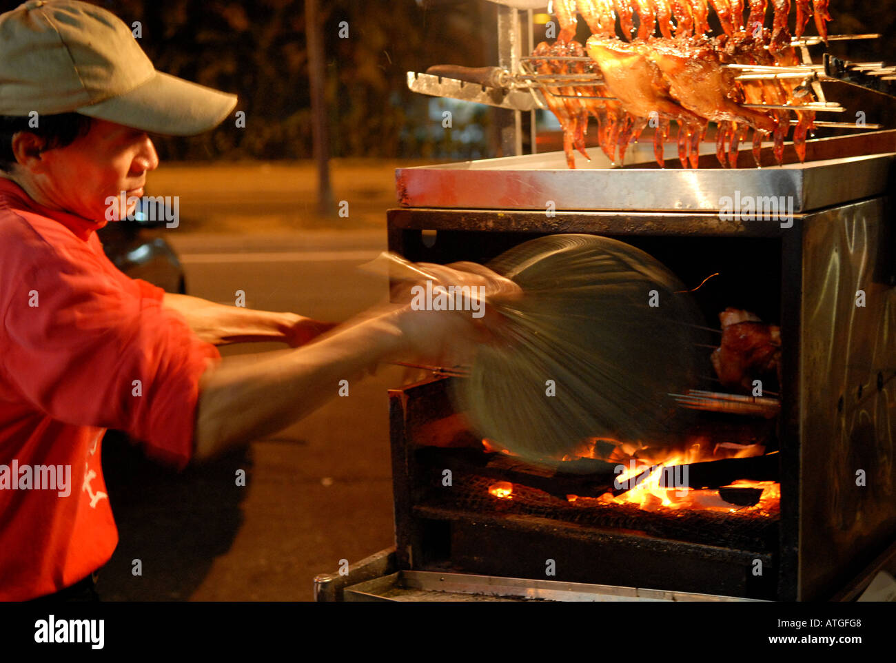 Hawker preparing barbequed chicken for his customers in Kuala Lumpur ...
