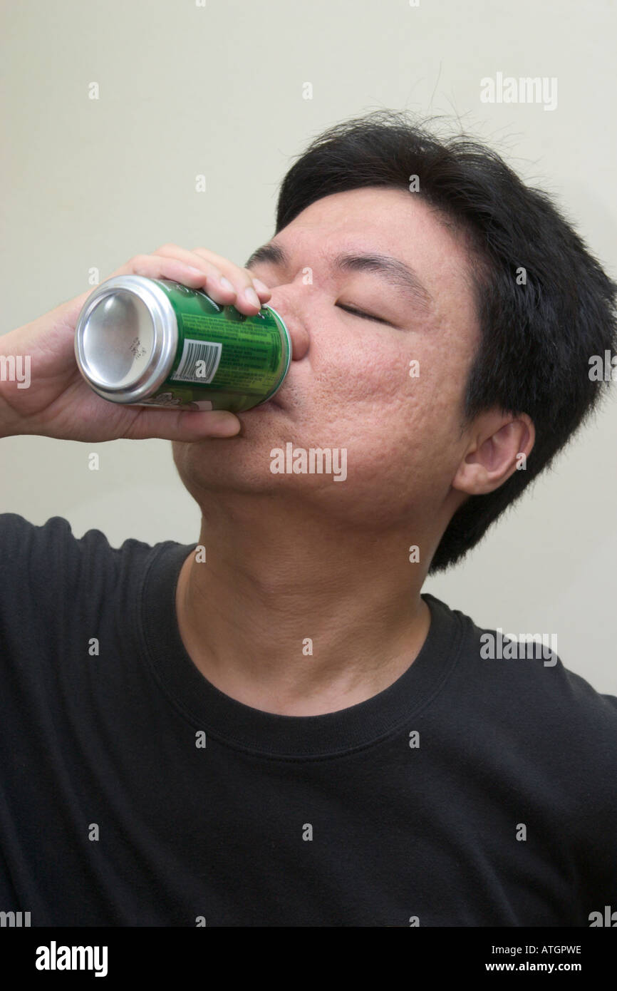 young asian man of chinese ethnicity drinking a can of soft drink Stock ...