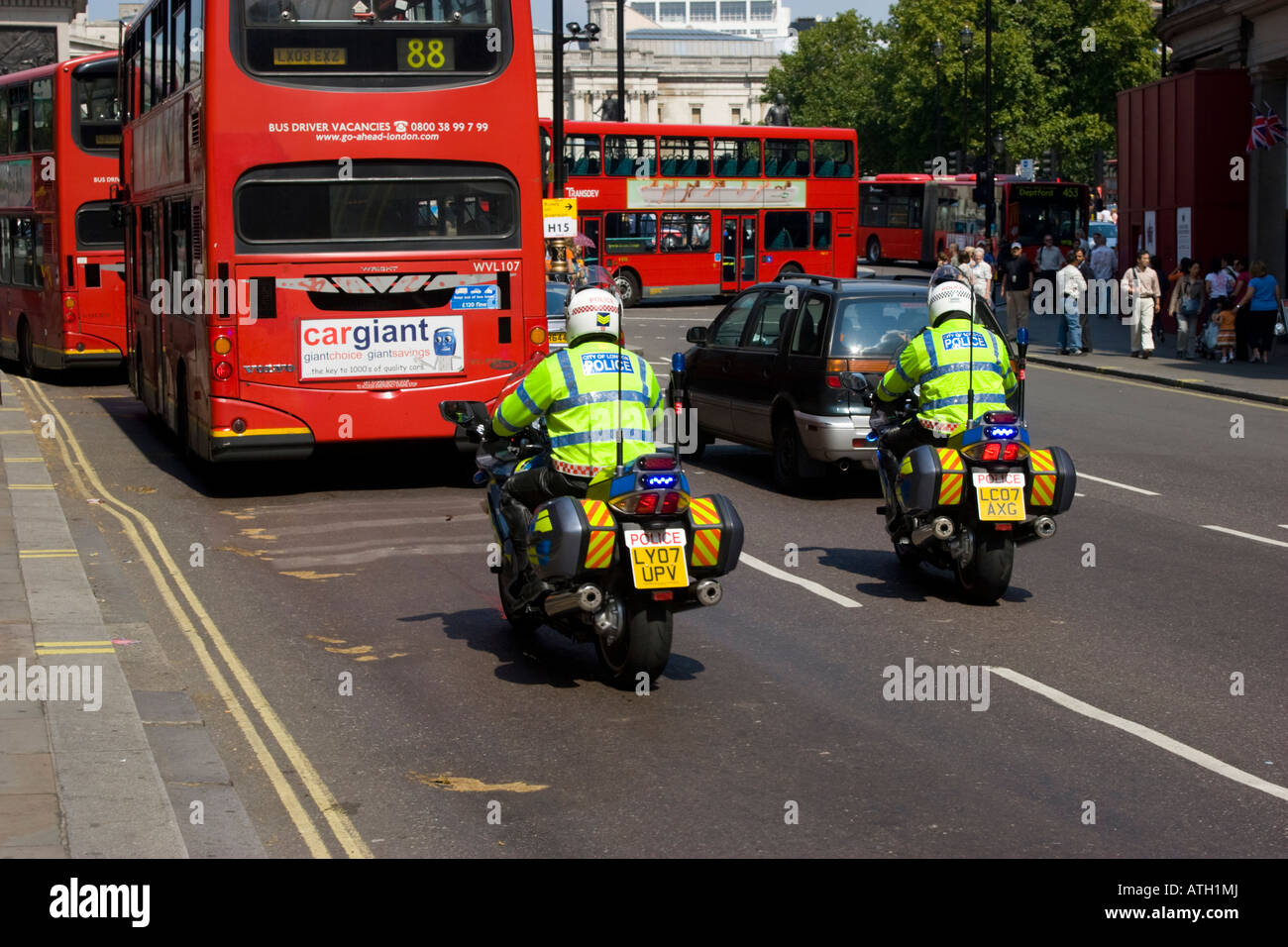 Police motorcyclists in queue of traffic behind London buses Stock ...