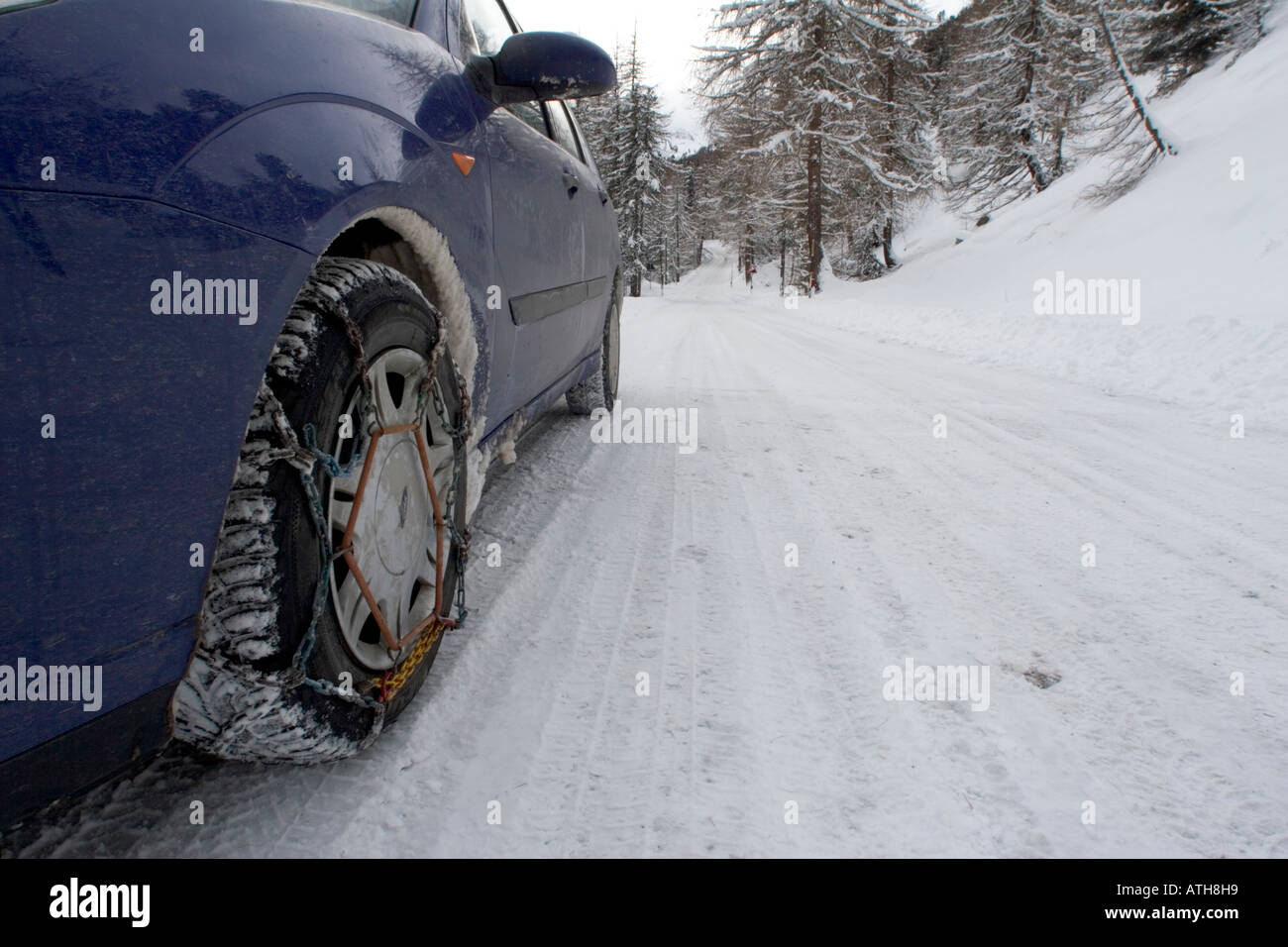 Snow chains on car wheel on compressed snow Stock Photo - Alamy