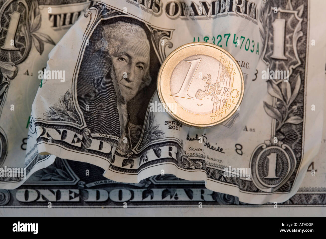 Shining 1 Euro coin lying on crumpled up and damaged 1 Dollar banknote ...