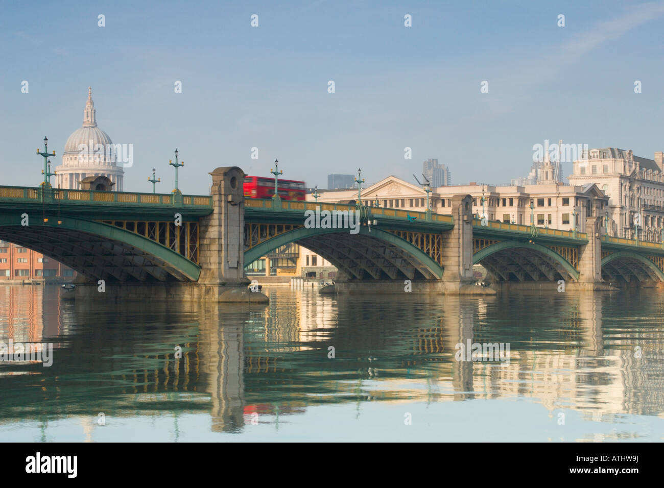 Red London bus travelling on Southwark Bridge over the River Thames. St ...