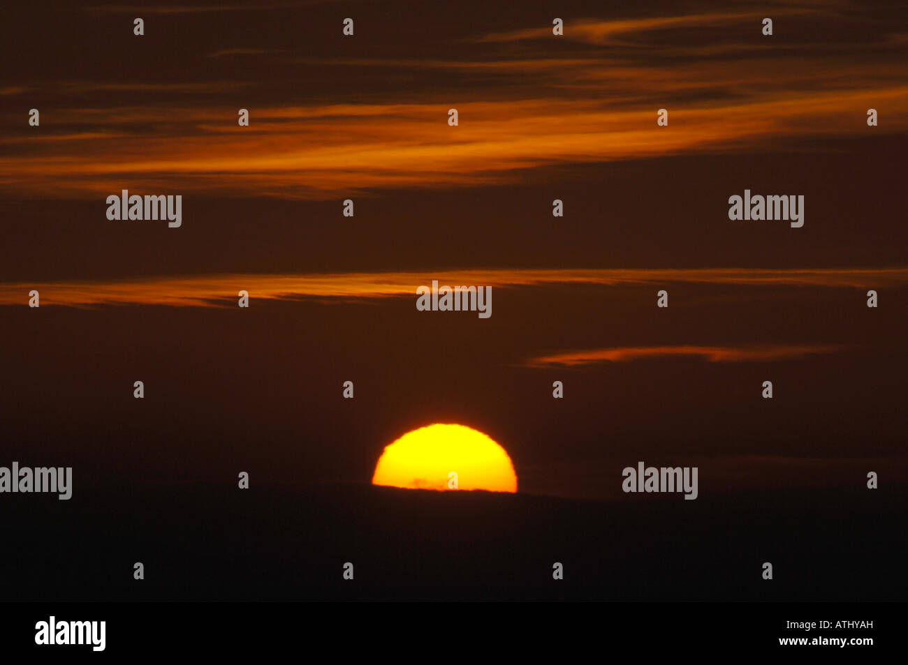 The Sun Setting Behind Clouds Stock Photo - Alamy