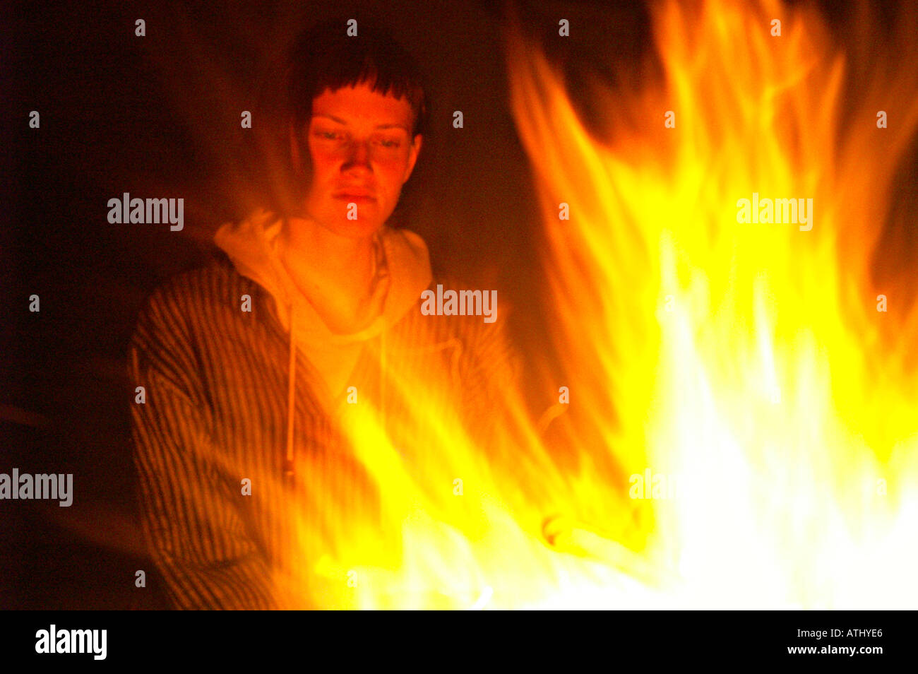 Pretty Girl, sitting by the fire, pondering Stock Photo - Alamy
