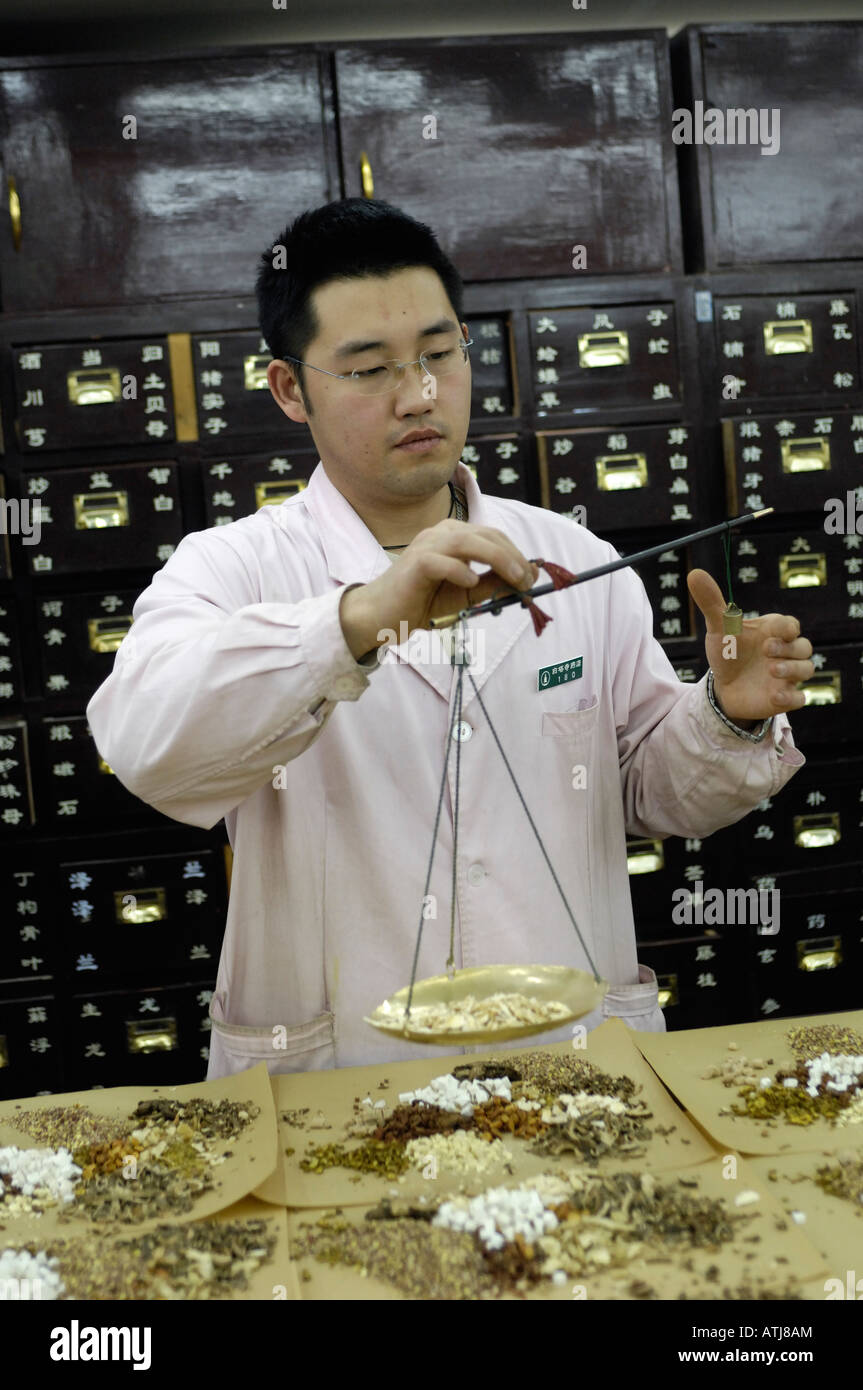 Chinese herbalist weighing herbal medicine using traditional scale in ...