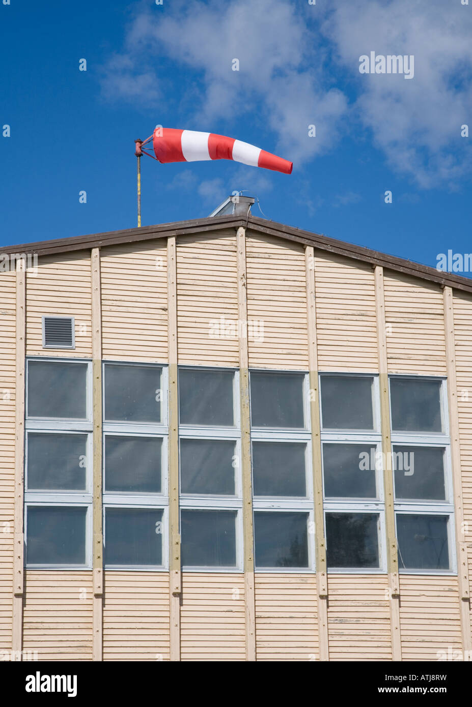Red and white colored windsock against blue sky at the hangar rooftop ...