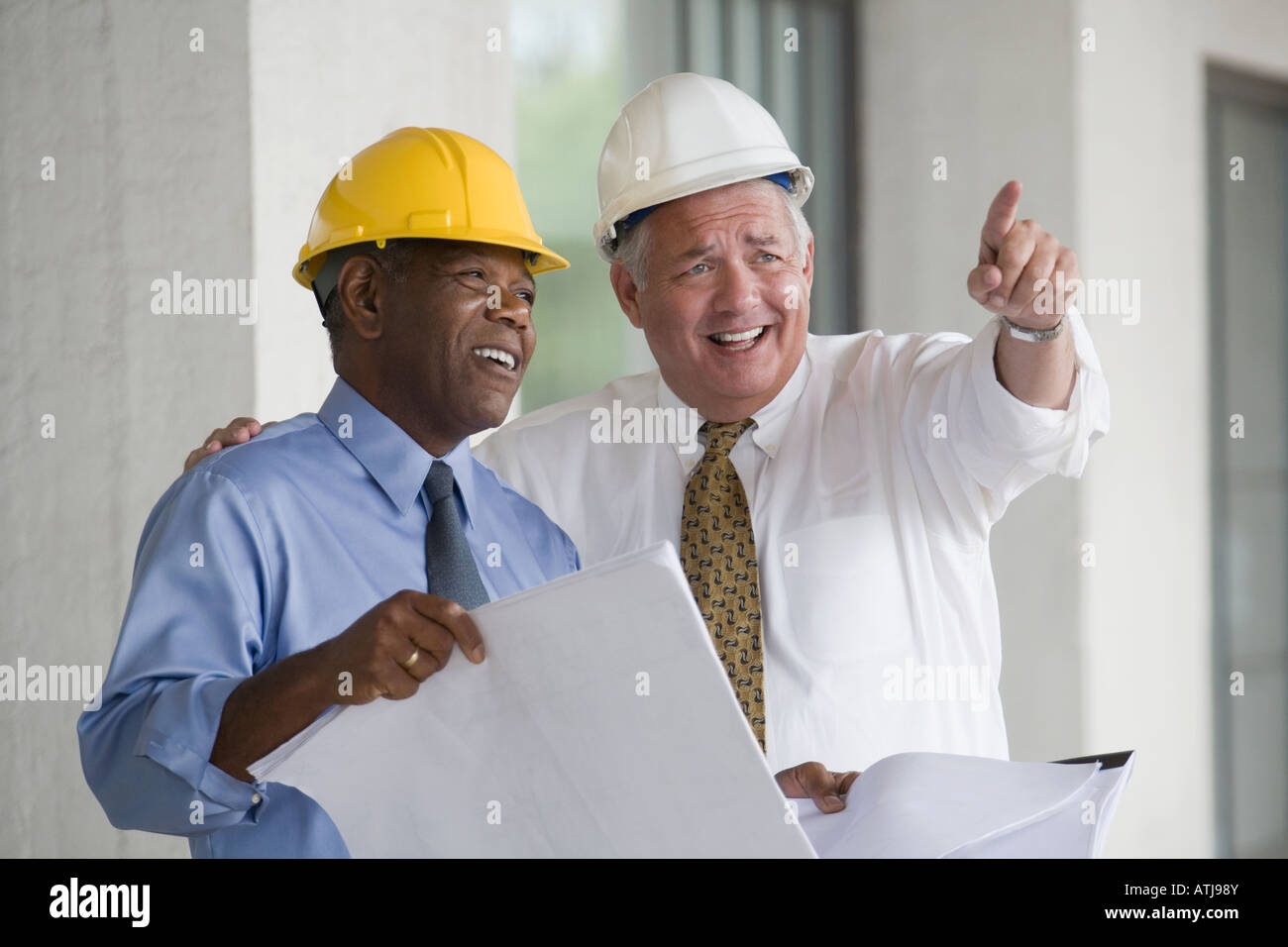 Two engineers discussing a blueprint and smiling Stock Photo - Alamy