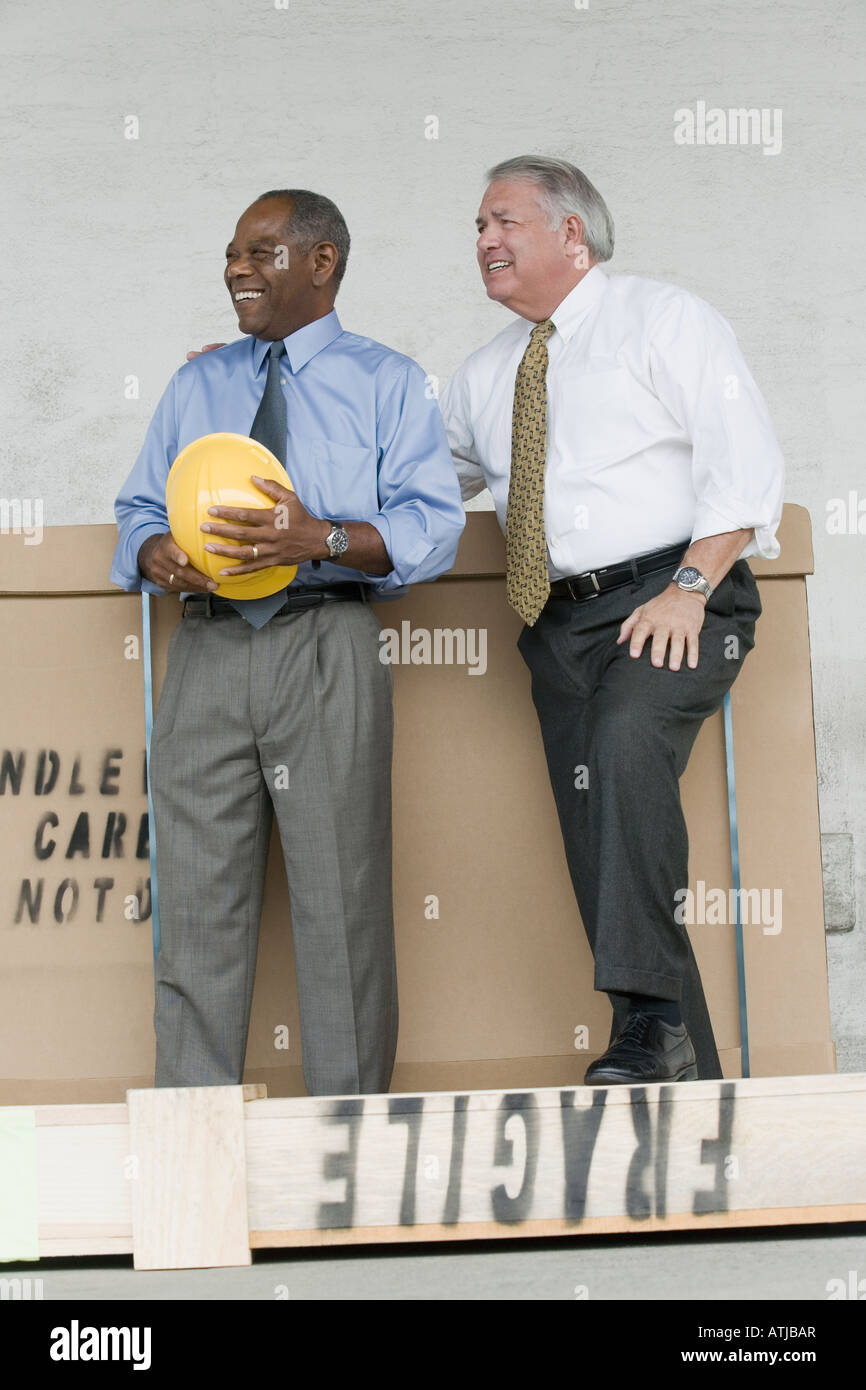Two engineers standing near a cardboard box and smiling Stock Photo - Alamy