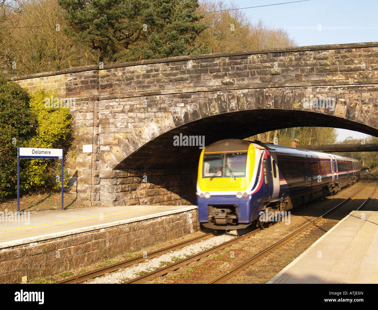 modern commuter train passing under bridge Stock Photo - Alamy