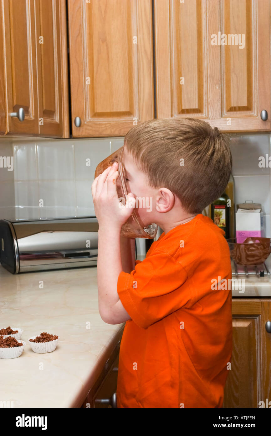 Young boy licking bowl clean after making chocolate crispies Stock ...