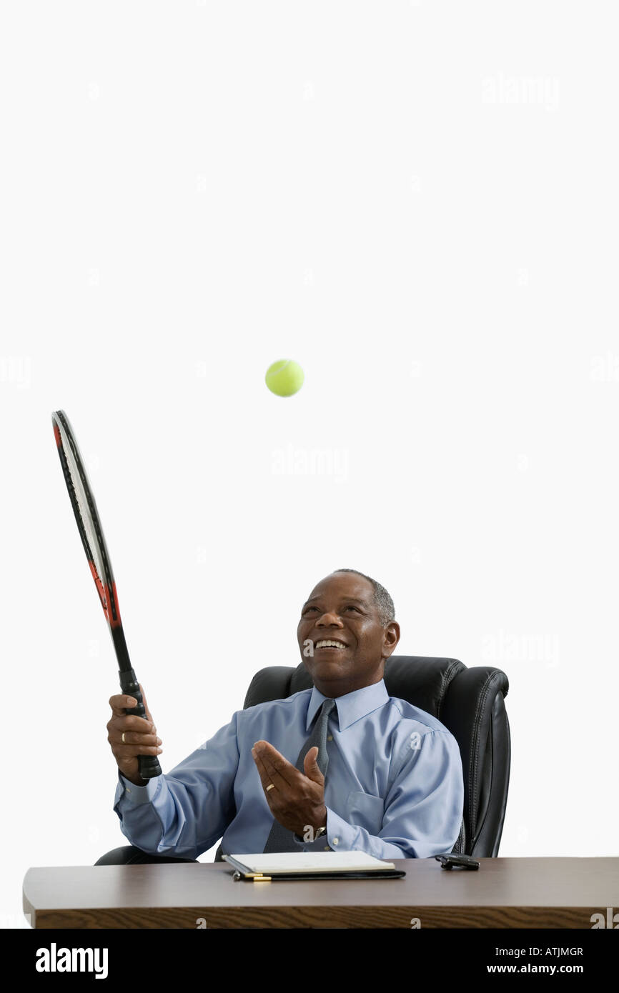 Businessman sitting at a desk and tossing a tennis ball Stock Photo - Alamy