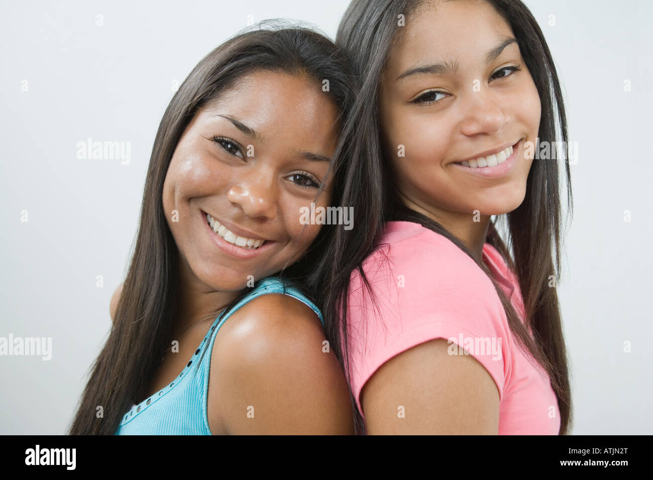 Portrait of two teenage girls back to back smiling Stock Photo - Alamy