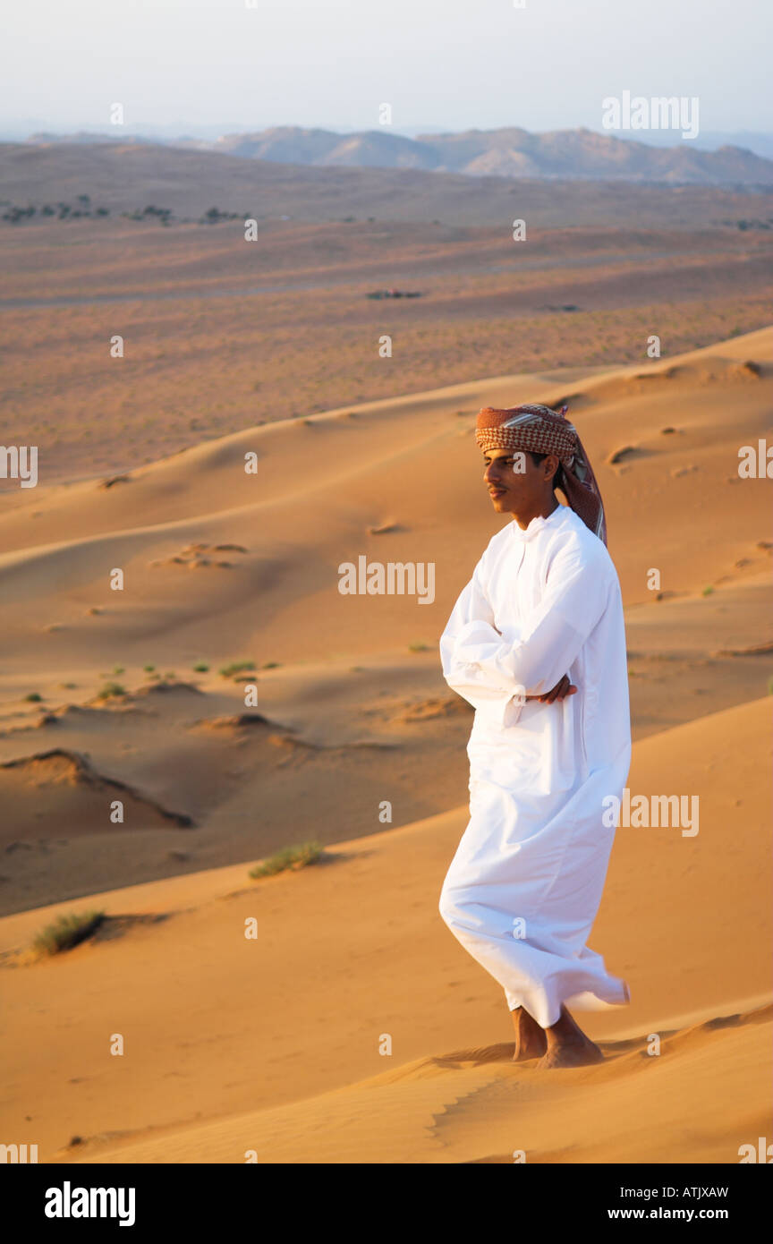 Bedu tribesman in traditional dishdasha dress on top of desert sand ...