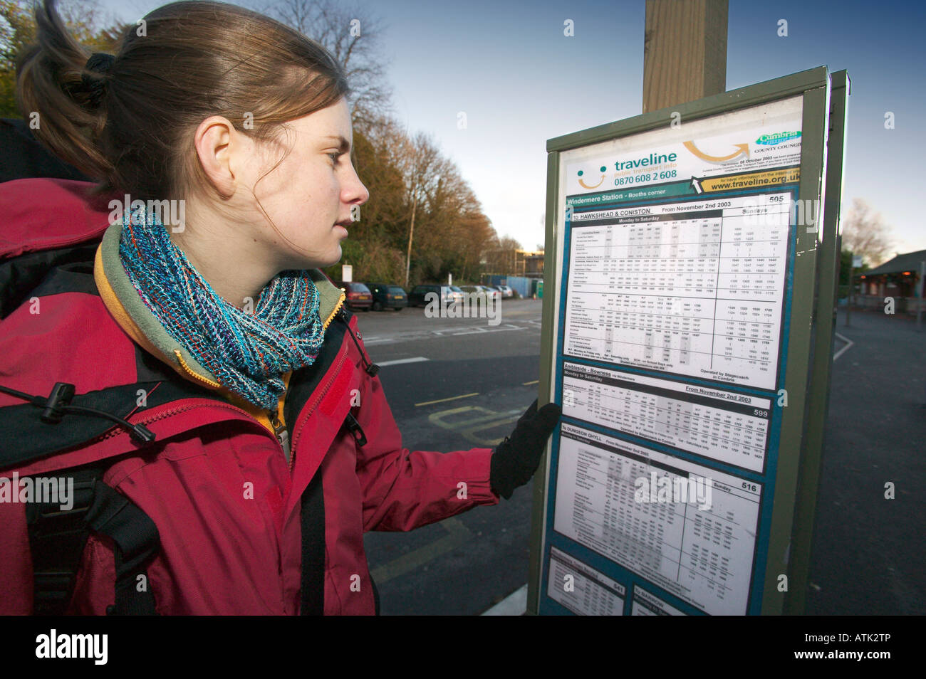 Woman at bus stop reading timetable Stock Photo - Alamy