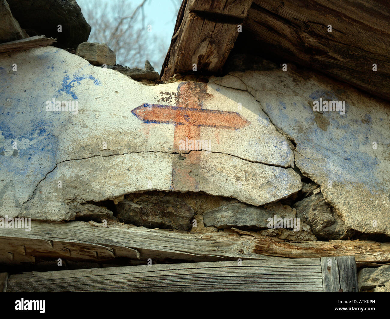 red pointed cross painted on crumbling cracked side of tumble down ...