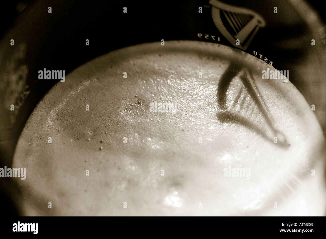 The Guinness symbol casts a shadow across the beers foam Stock Photo ...