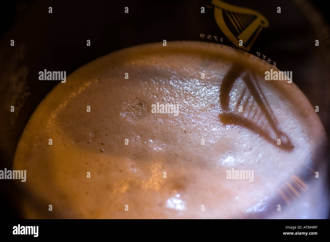 The Guinness symbol casts a shadow across the beers foam Stock Photo ...