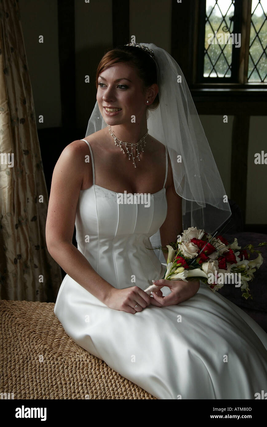 Bride posing for photograph before wedding ceremony and looking out of ...