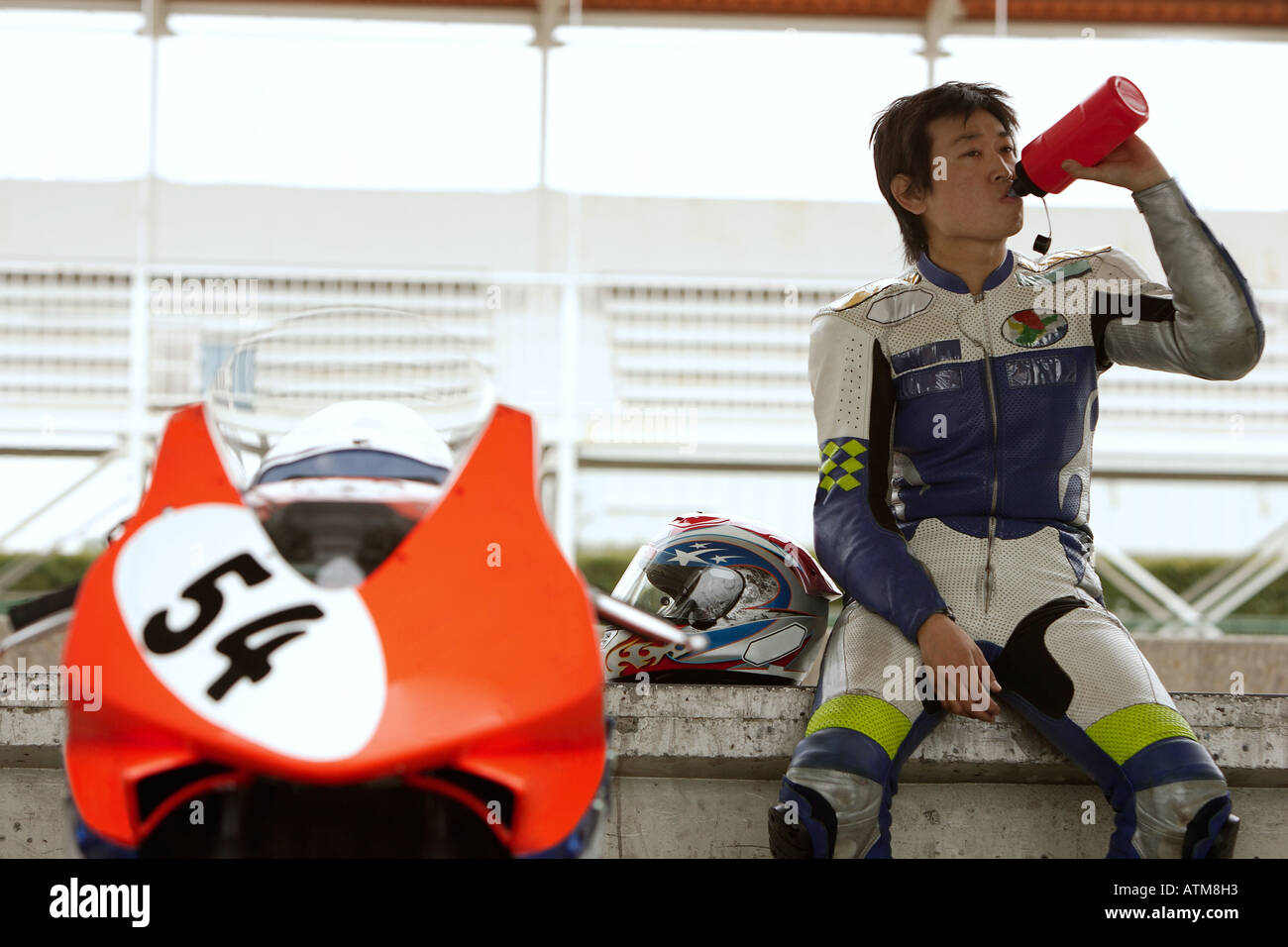 Asian racing motor biker drinking from flask Stock Photo - Alamy