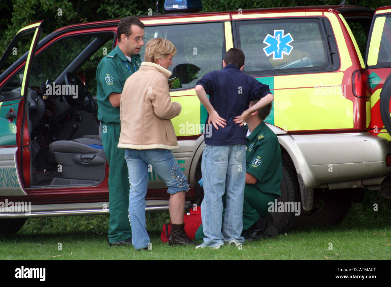 A woman with trouser leg rolled up is consulting two paramedics by a ...