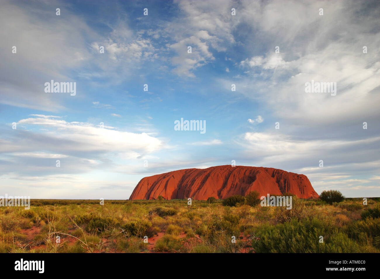 Ayers rock Uluru glows red as storm coulds gather in a blue sky in late ...