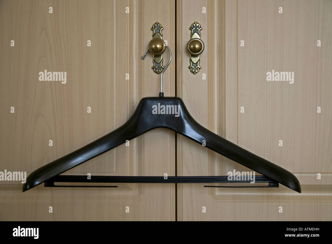 Black plastic coat hanger hanging on handle of door of wardrope Stock ...