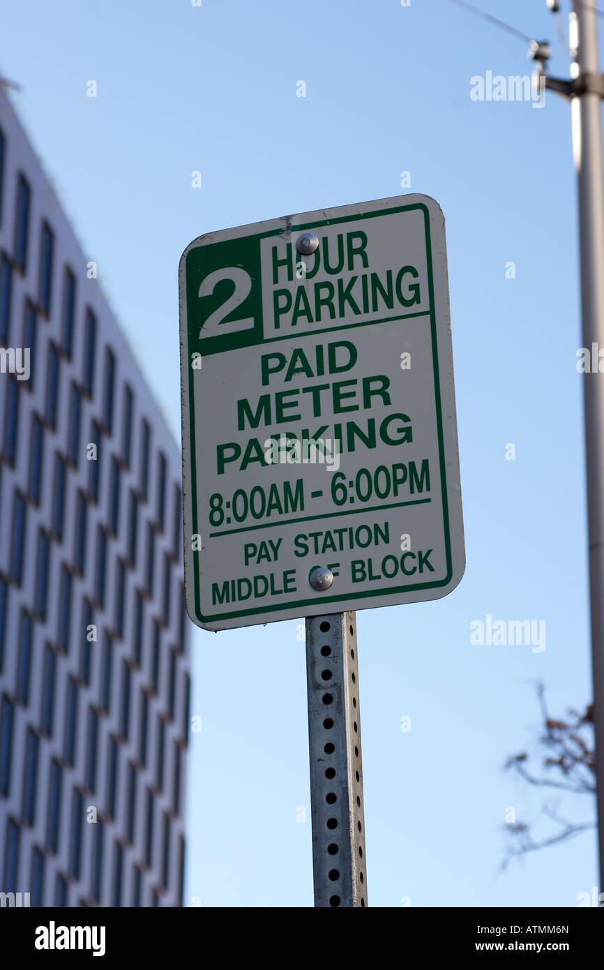 A "2 Hour parking" traffic sign against a shady downtown background ...