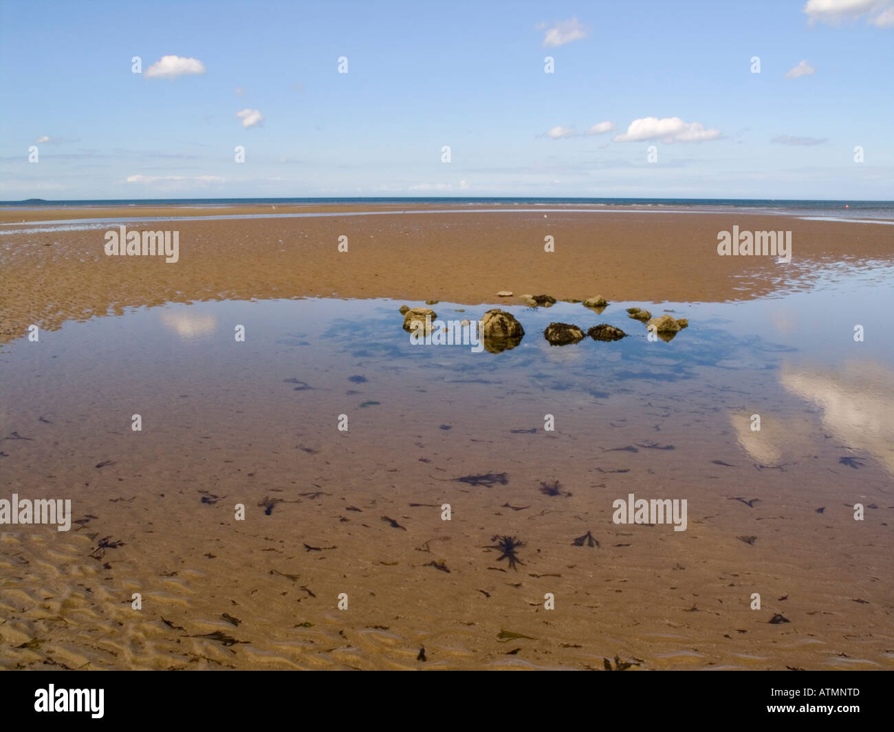 Tidal pool on an empty beach in sand at low tide in summer. Red Wharf ...