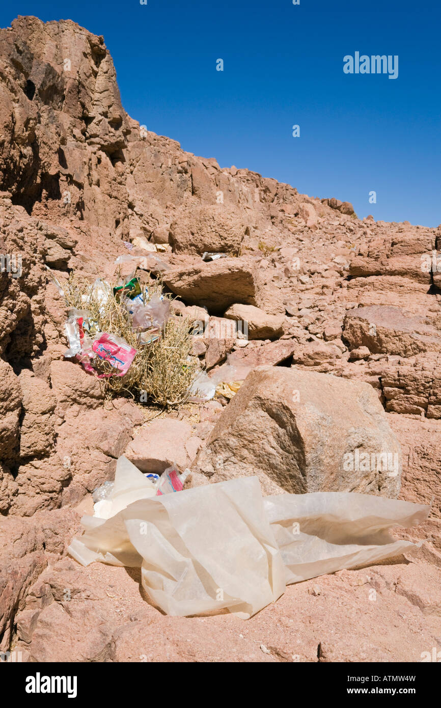 Rubbish littering rocks in remote desert habitat bags packets plastic ...